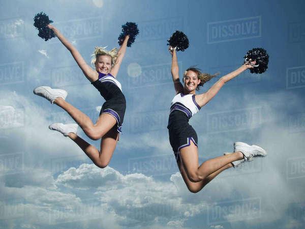 Cheerleaders with pom poms jumping - Stock Photo - Dissolve