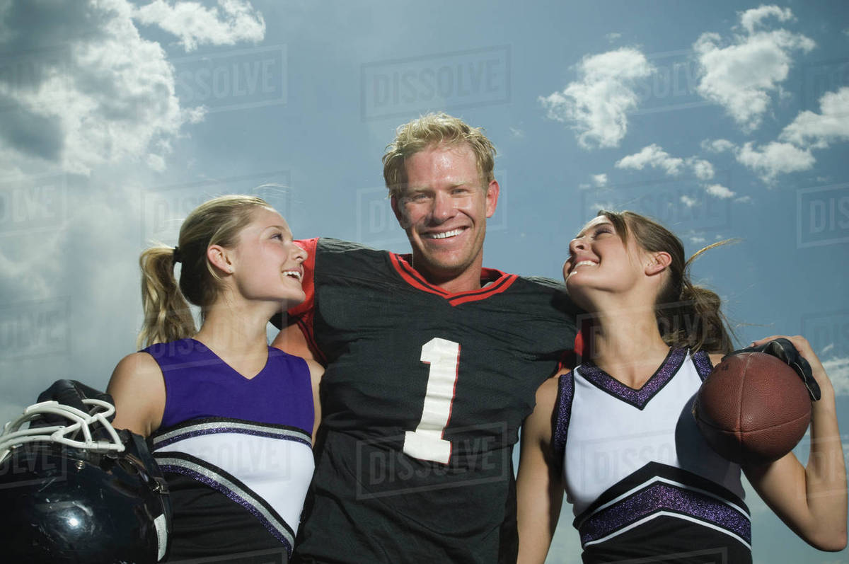 Football player hugging cheerleaders - Stock Photo - Dissolve