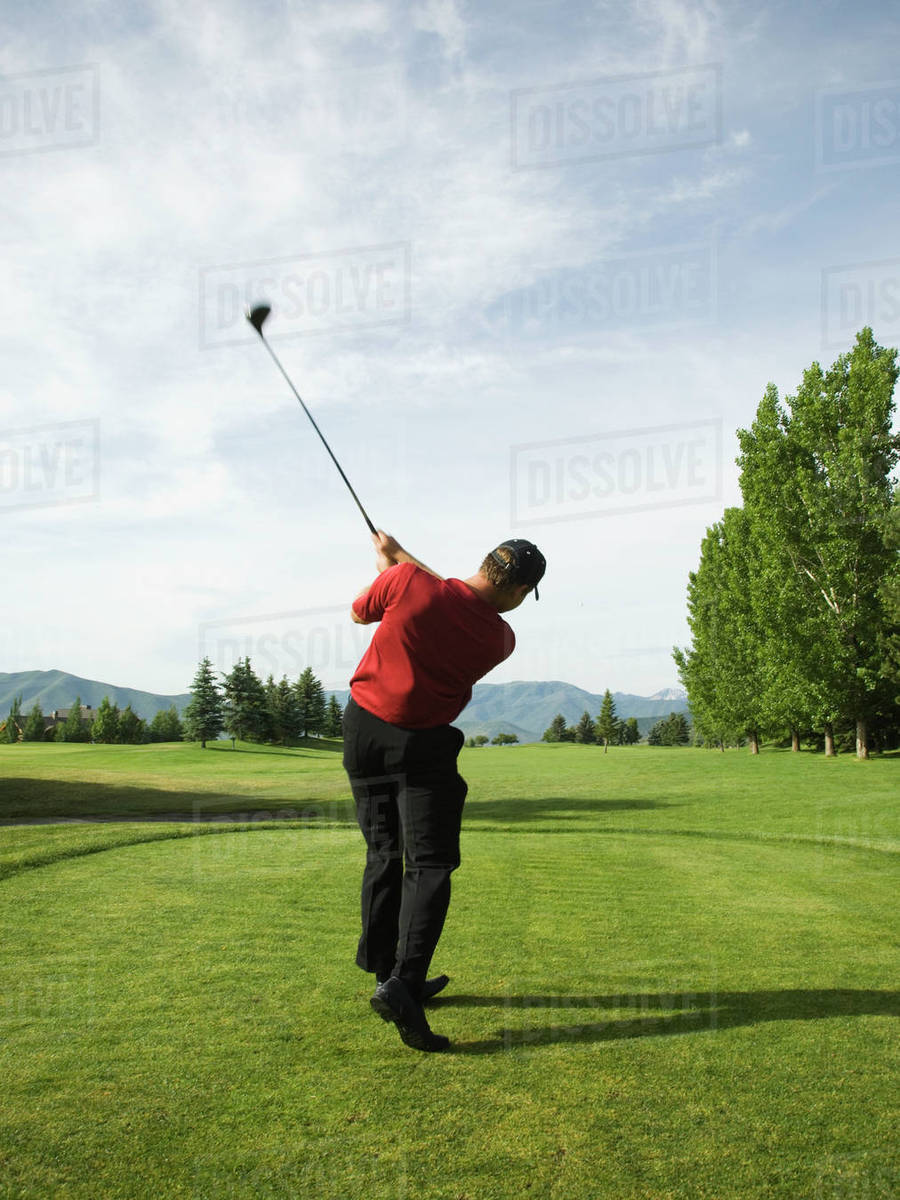 Man swinging golf club - Stock Photo - Dissolve