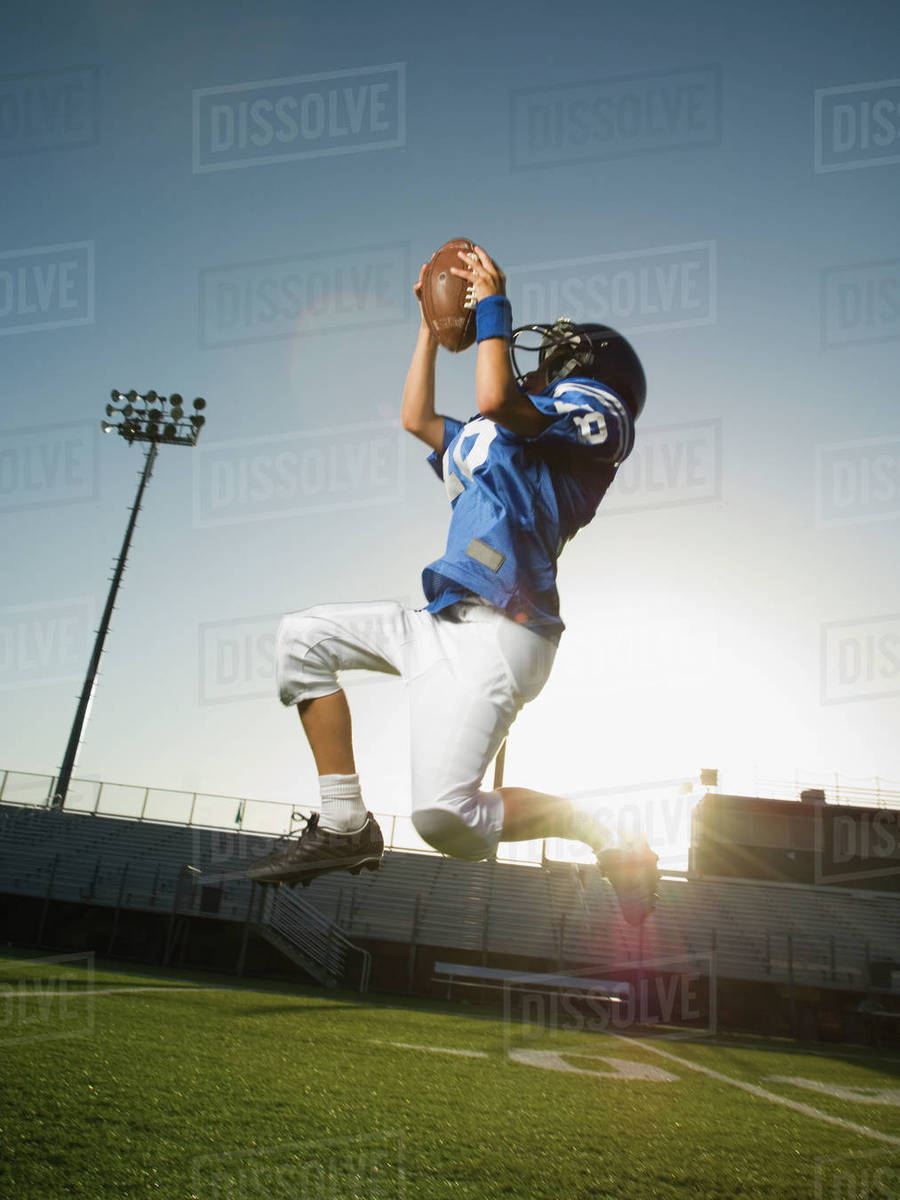 Young football player catching ball - Stock Photo - Dissolve