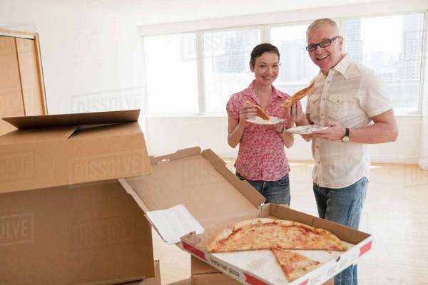 Portrait of smiling couple eating pizza in new apartment - Stock Photo ...