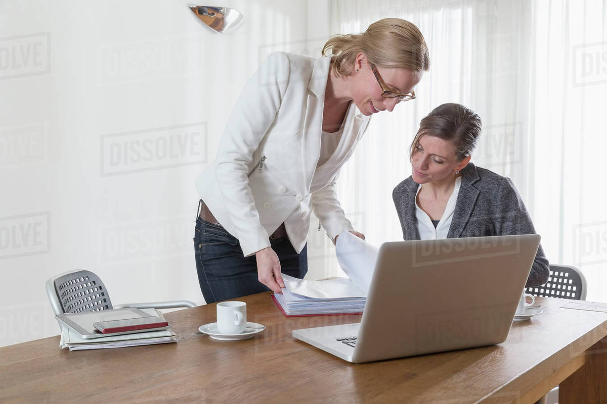 Businesswomen looking at documents at office - Stock Photo - Dissolve