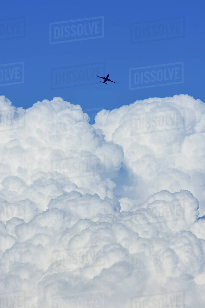 Airplane flying over large cloud - Royalty-free Stock Photo | Dissolve