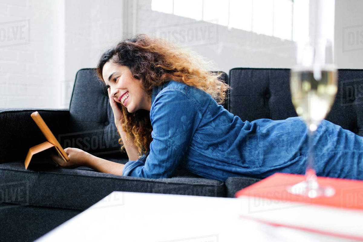 Woman watching tablet on sofa - Royalty-free Stock Photo | Dissolve