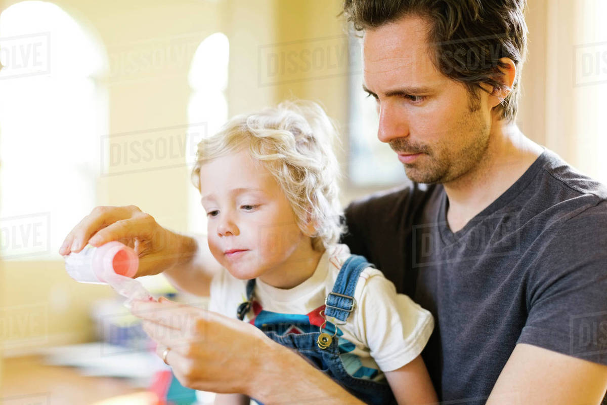 Father applying medicine to son (4-5) - Royalty-free Stock Photo | Dissolve