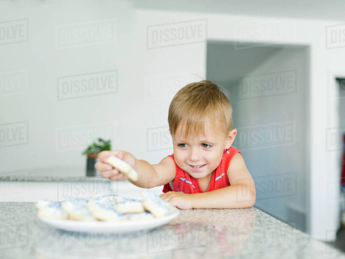 Boy (2-3) reaching for cookies on kitchen counter - Royalty-free Stock ...