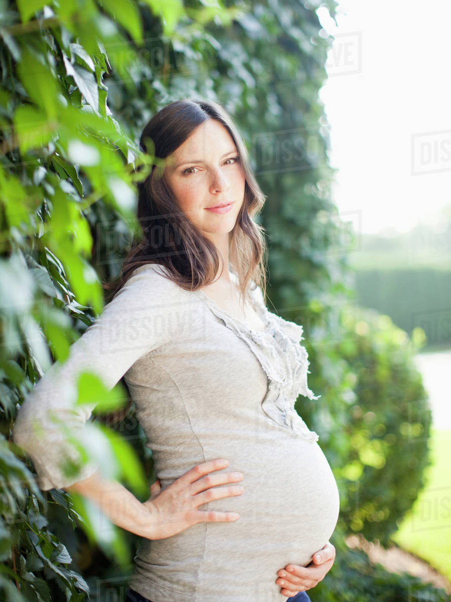 Portrait of pregnant mid adult woman next to hedge - Royalty-free Stock ...