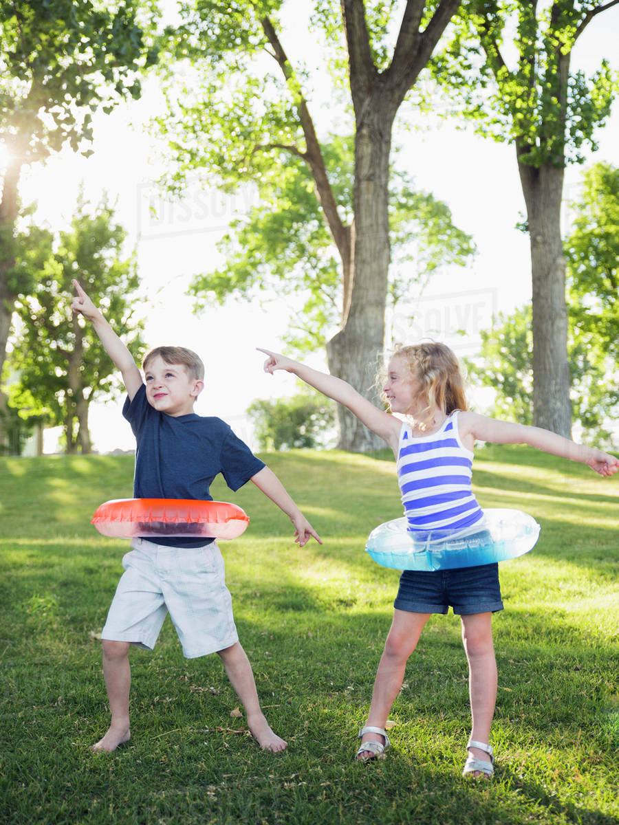 Two kids (4-5, 6-7) playing with inflatable rings in park - Royalty ...