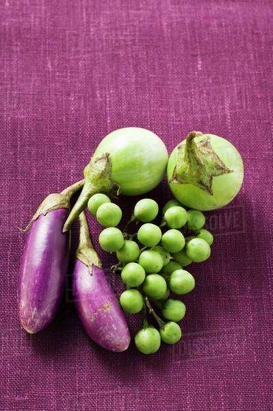 Various types of aubergines on purple background - Stock Photo - Dissolve