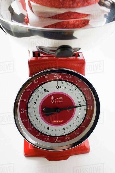 Kitchen scales with raw burgers - Royalty-free Stock Photo | Dissolve