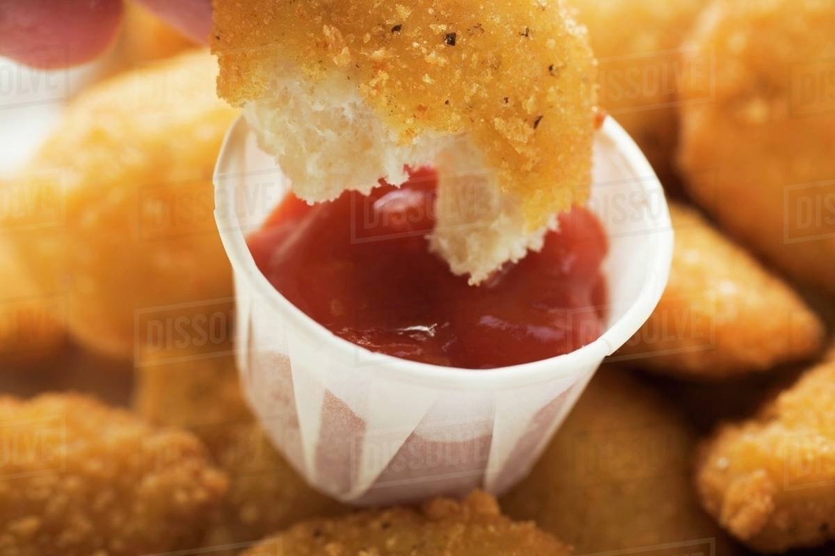 Dipping a chicken nugget in ketchup - Royalty-free Stock Photo | Dissolve