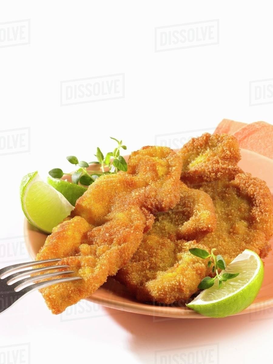 Breaded escalopes with lime wedges - Stock Photo - Dissolve
