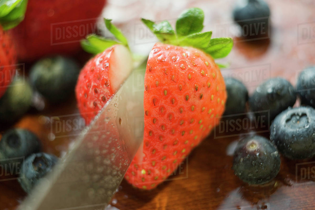 Cutting a strawberry in half - Royalty-free Stock Photo | Dissolve