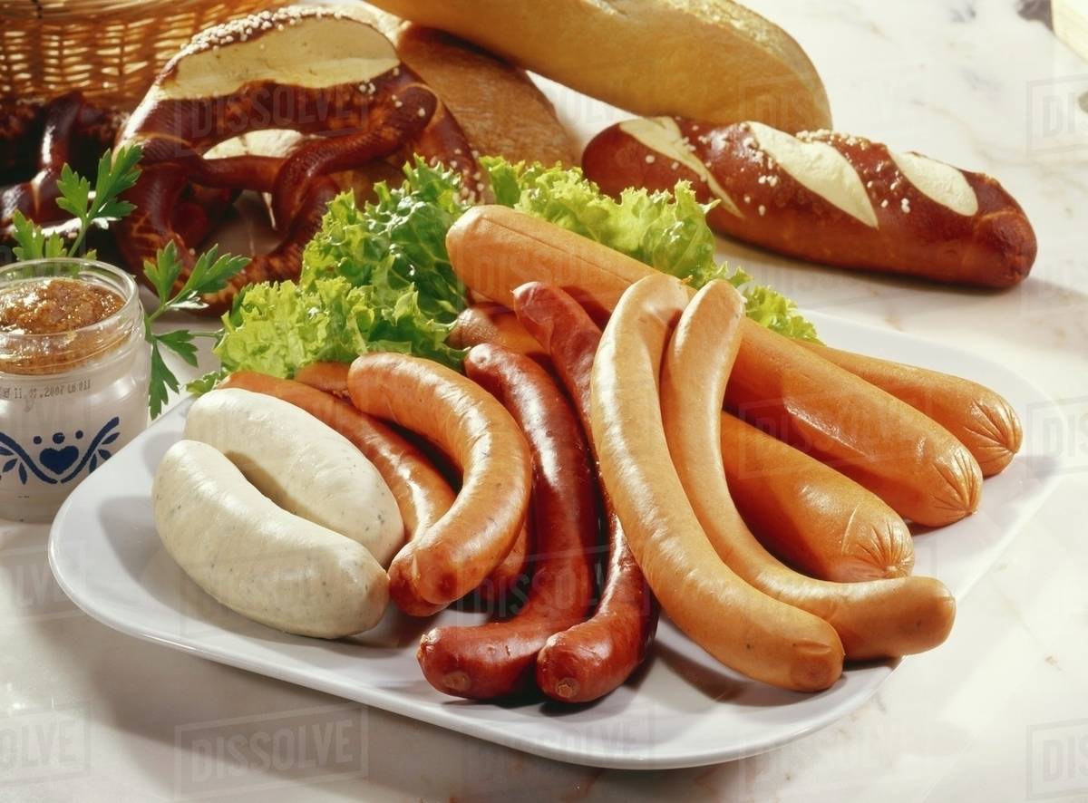 Mixed sausages on a platter, bread rolls and mustard behind - Royalty ...