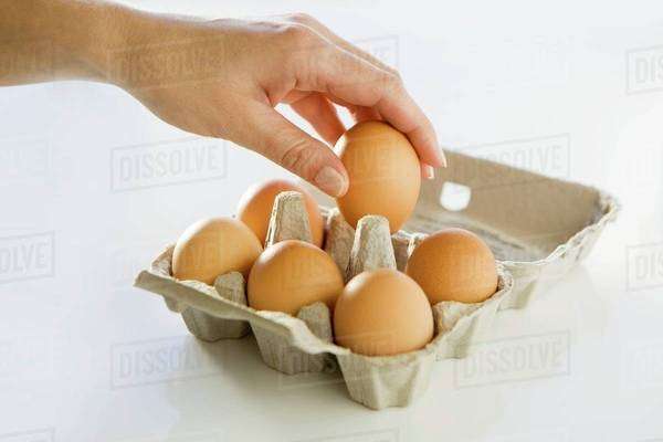 Hand taking egg out of egg box - Royalty-free Stock Photo | Dissolve