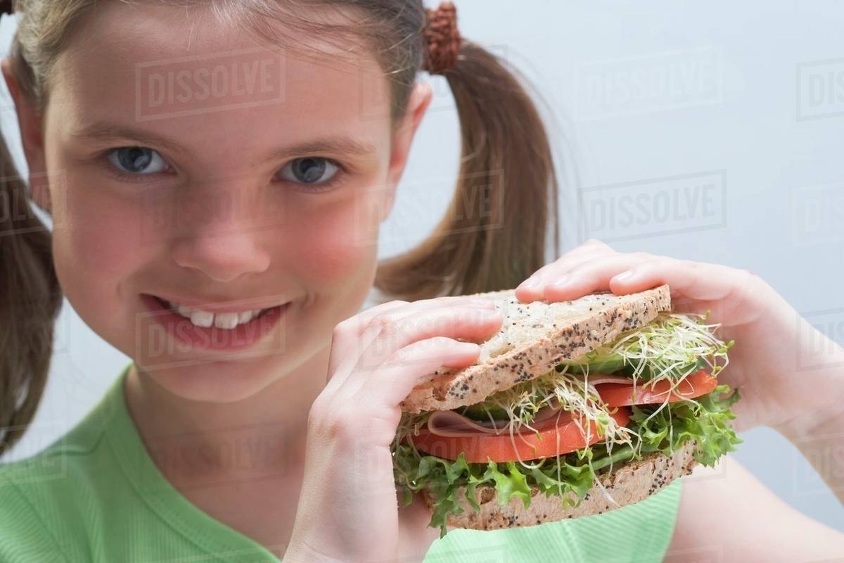 Smiling girl holding a sandwich - Stock Photo - Dissolve