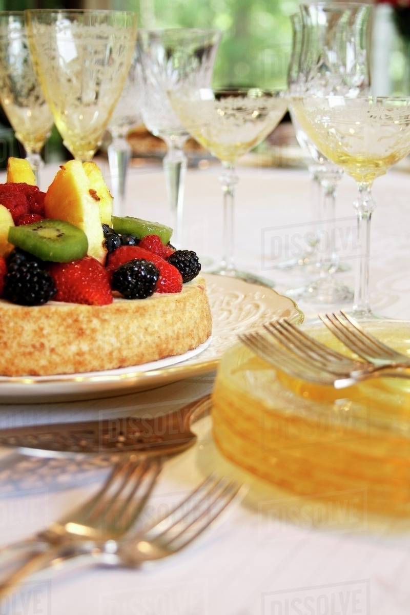 Fruit Tart on Table with Stacked Plates and Stem Glasses - Royalty-free ...