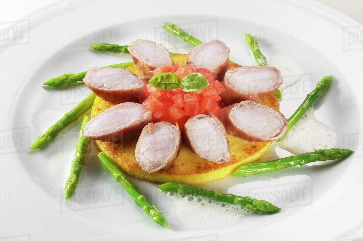 Rabbit loin & diced tomato on pancake, surrounded by asparagus - Stock ...
