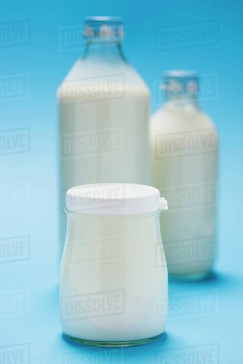 Natural yoghurt in jar, bottles of milk in background - Stock Photo ...