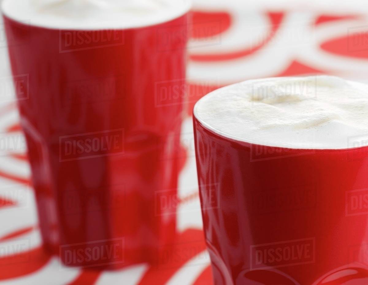 Coffee with milk froth in red beakers - Royalty-free Stock Photo | Dissolve