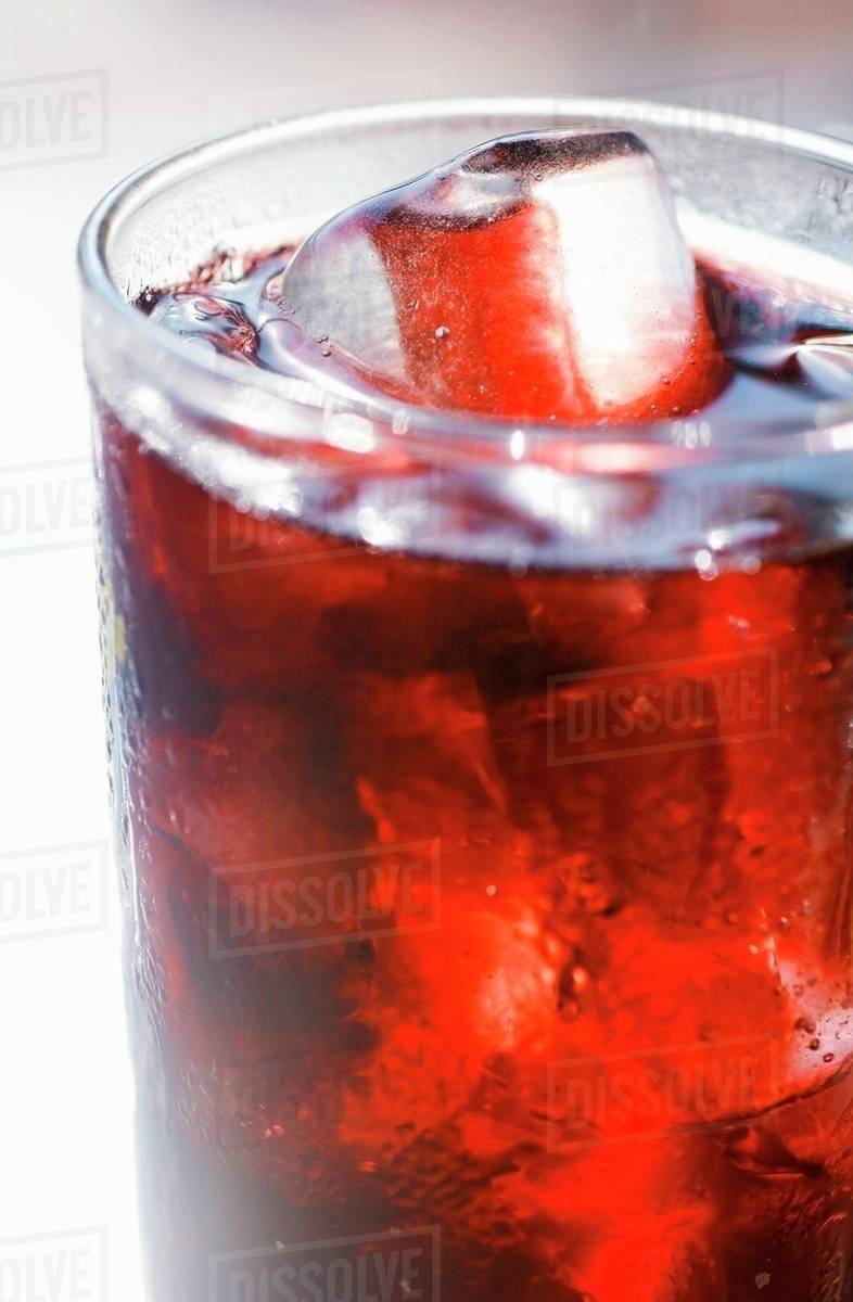 Red fruit juice with ice cubes in a glass - Stock Photo - Dissolve