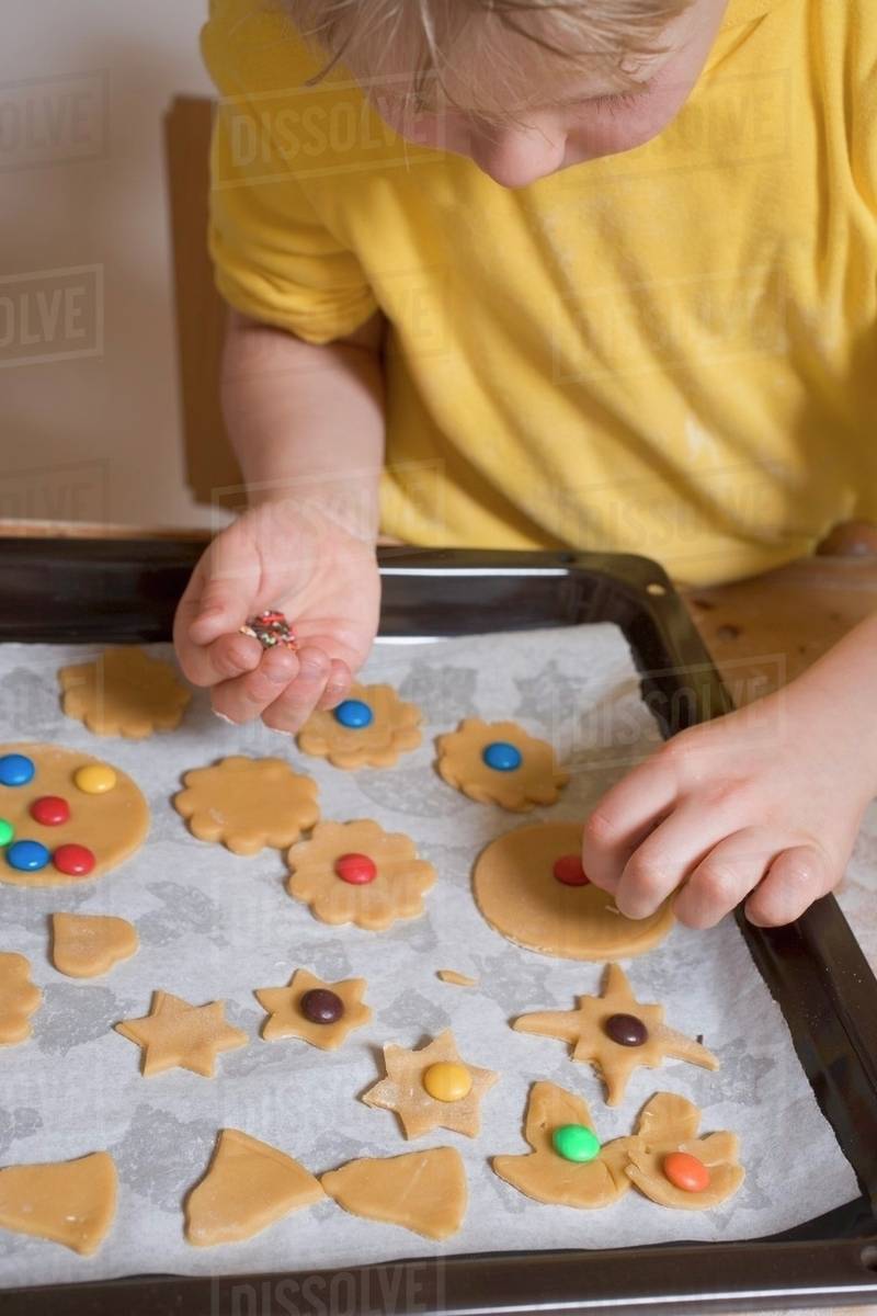 Child decorating biscuits with coloured chocolate beans - Royalty-free ...