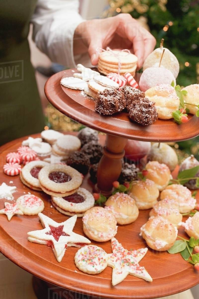 Hand reaching for Christmas biscuits on tiered stand - Stock Photo ...