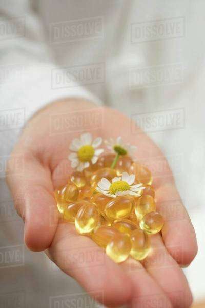 Hand holding vitamin capsules and chamomile flowers - Royalty-free ...
