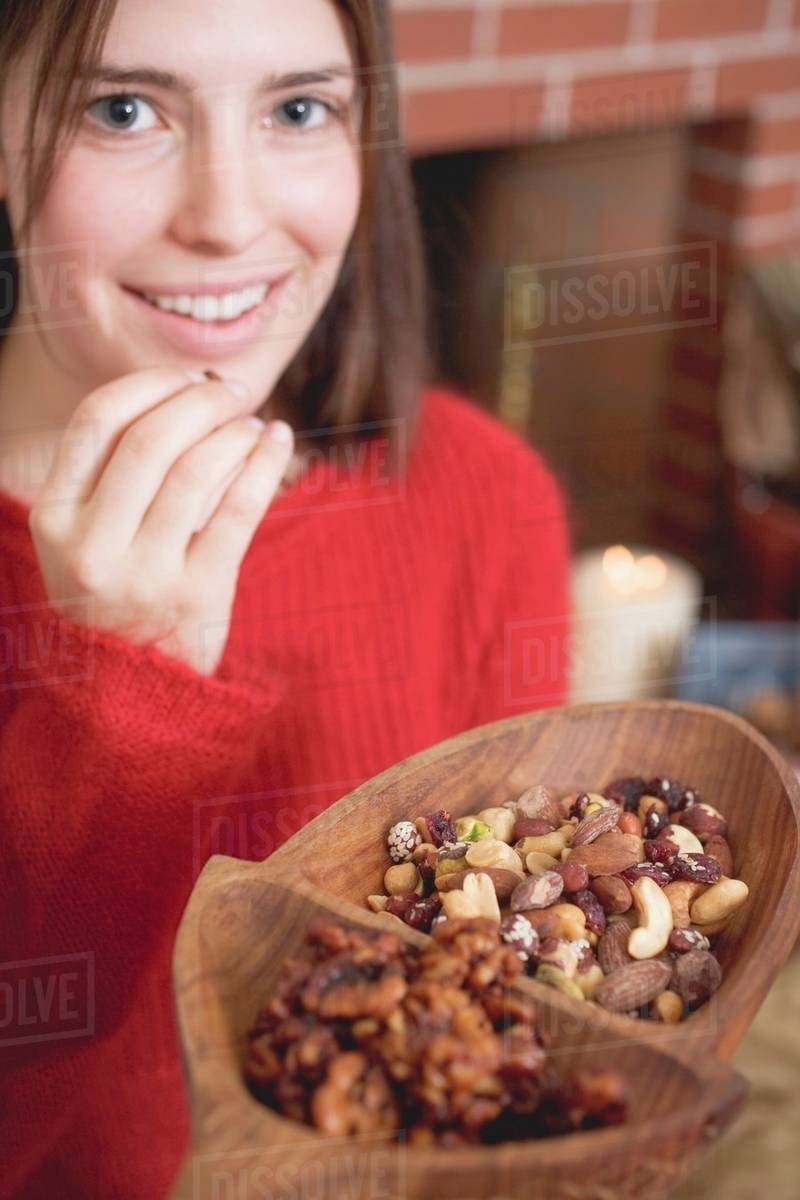 Young woman eating nuts in front of fireplace (Christmas) - Royalty ...