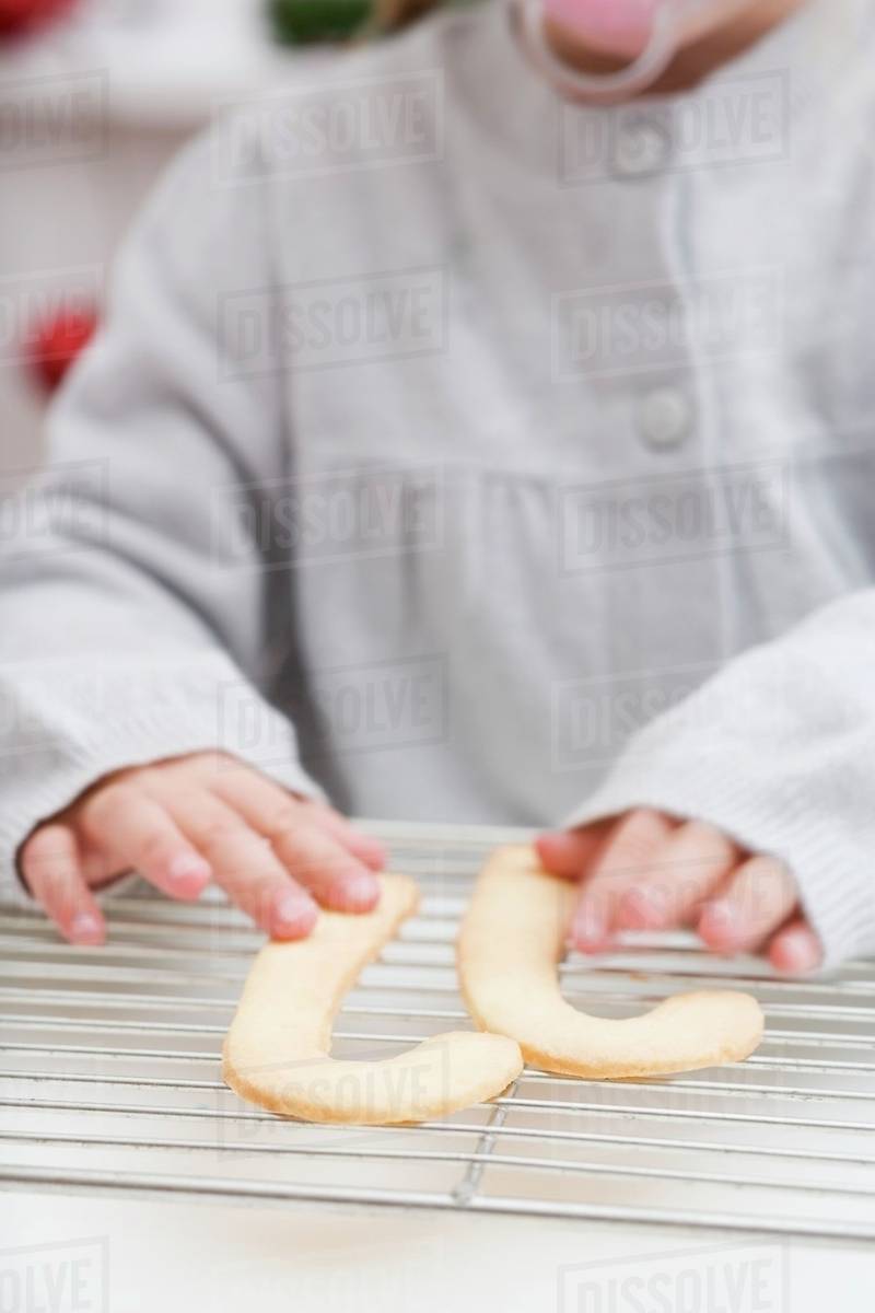 Child reaching for candy cane biscuits on cake rack - Royalty-free ...