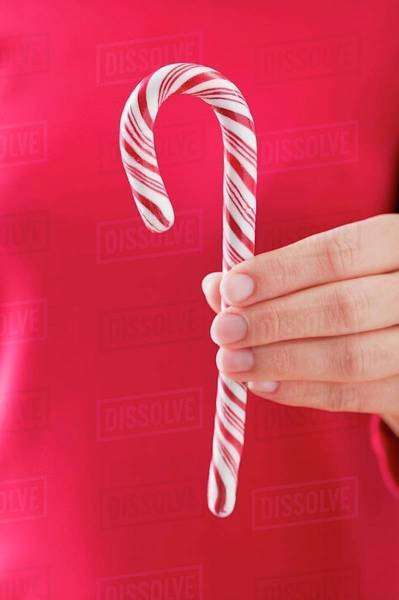 Hand holding candy cane - Royalty-free Stock Photo | Dissolve