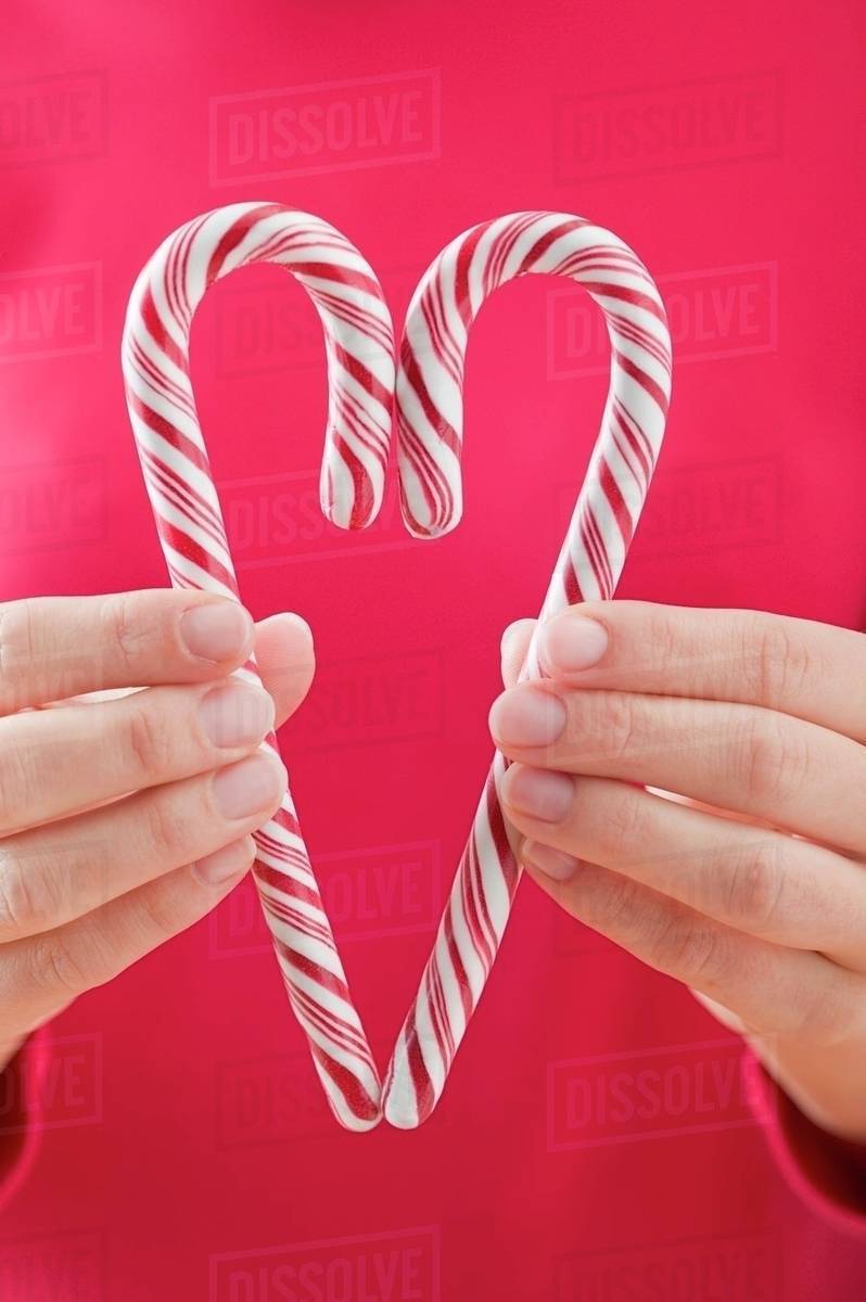 Woman holding two candy canes together to form a heart - Stock Photo ...