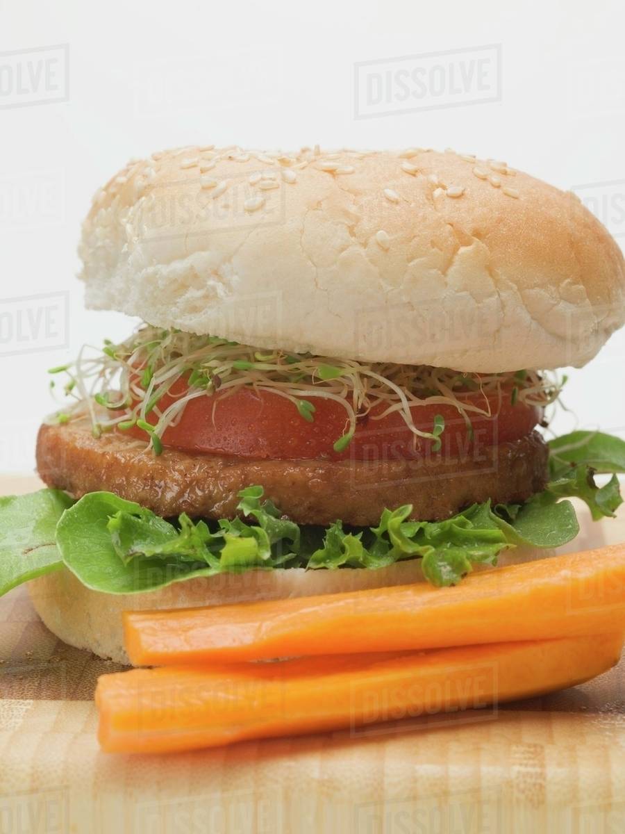 Burger with sprouts and tomato, carrots beside it - Stock Photo - Dissolve
