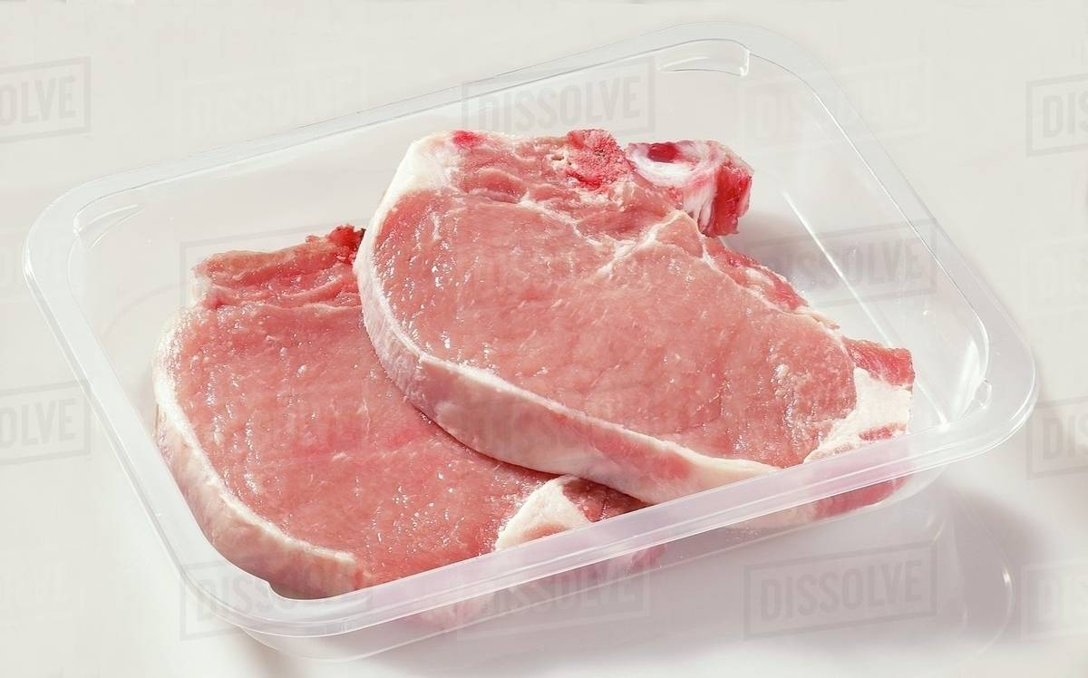 Two pork chops in plastic container - Stock Photo - Dissolve