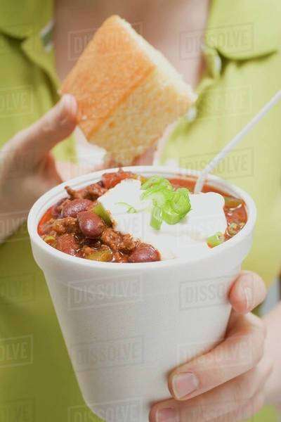 Woman holding chili con carne in paper cup and cornbread - Royalty-free ...