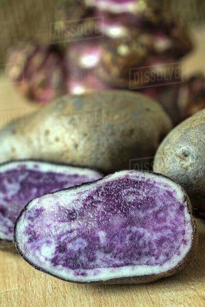 Blue Congo potatoes, whole and sliced on a wooden board - Royalty-free ...