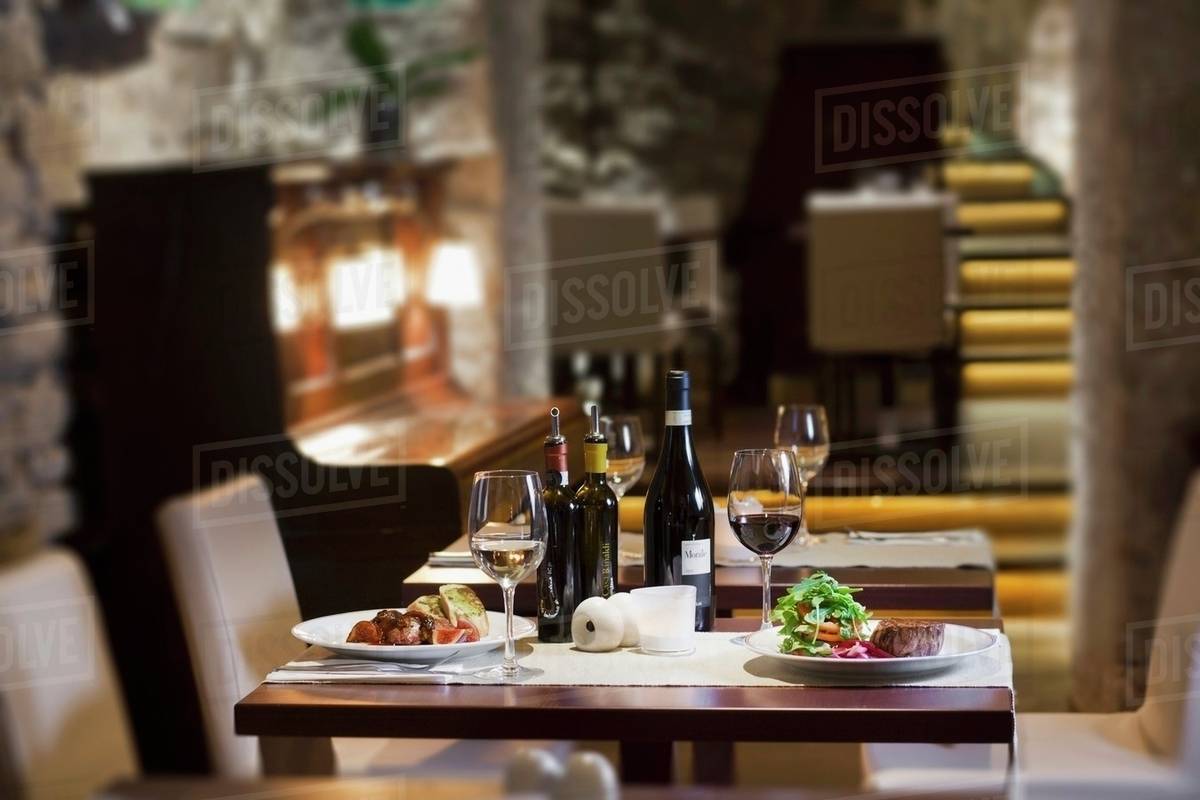 A view on the interior of the restaurant, a table set for two with wine ...