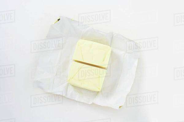 A pat of butter, halved, on paper - Royalty-free Stock Photo | Dissolve