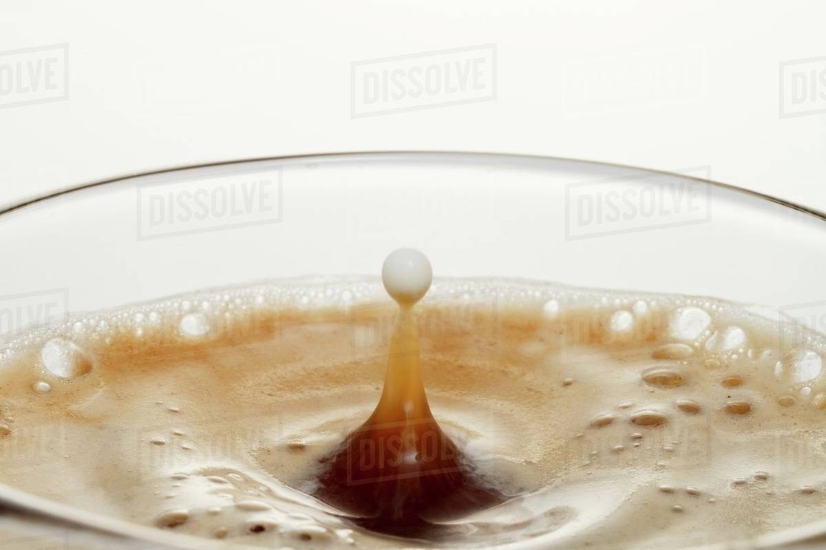 Cream dropping into coffee (close up) - Royalty-free Stock Photo | Dissolve