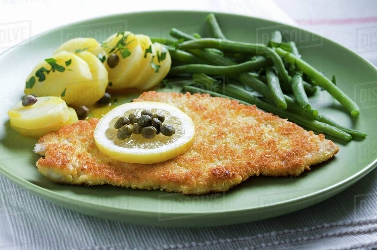 Bread turkey escalope with potatoes, capers and beans - Royalty-free ...