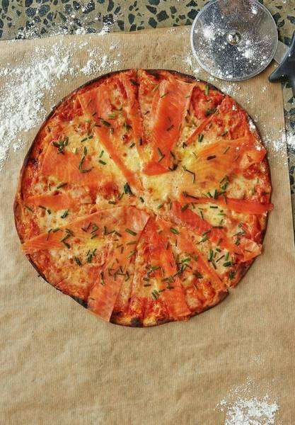 Salmon pizza on a piece of baking paper (seen from above) - Stock Photo ...