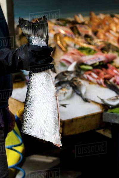 A fish seller holding a halved salmon at a fish market - Stock Photo ...