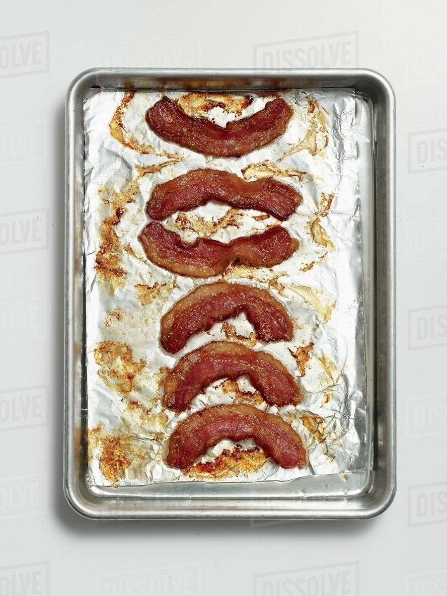 Roasted rashers of bacon on a baking tray lined with tin foil - Royalty ...