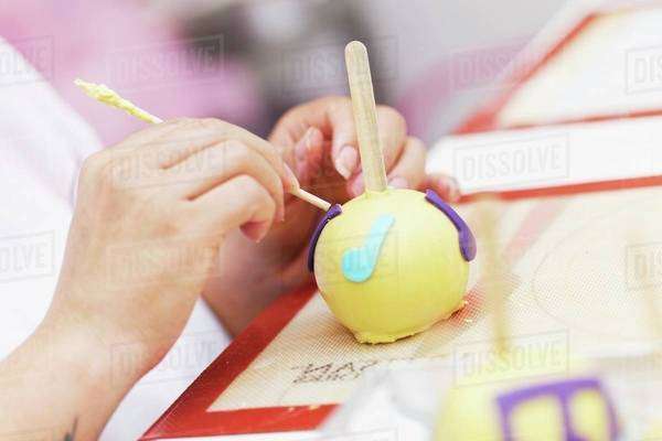 A giant cake pop being decorated with music notes - Stock Photo - Dissolve
