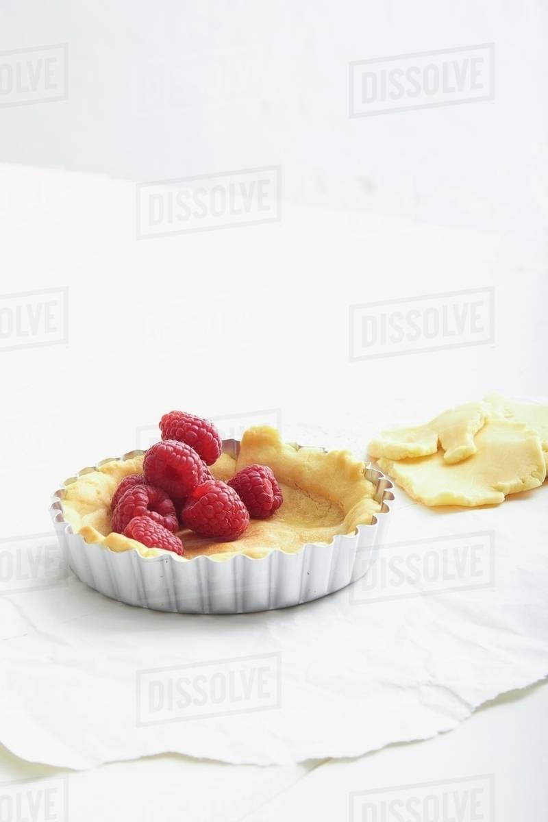 Unbaked shortcrust pastry in a tartlet dish with fresh raspberries ...