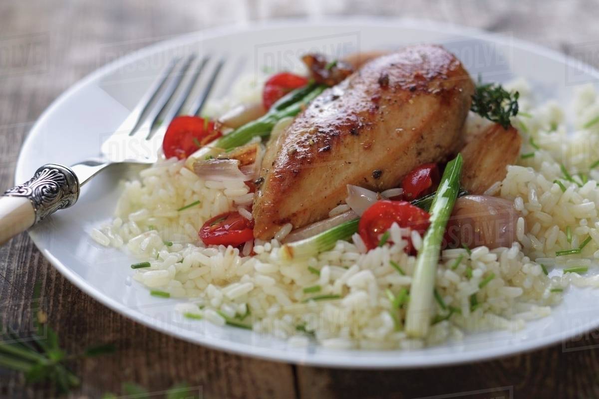 Chicken breast with onions and tomatoes on a bed of rice - Stock Photo ...