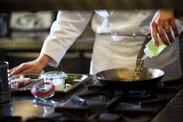 A chef preparing a steak in a commercial kitchen - Royalty-free Stock ...