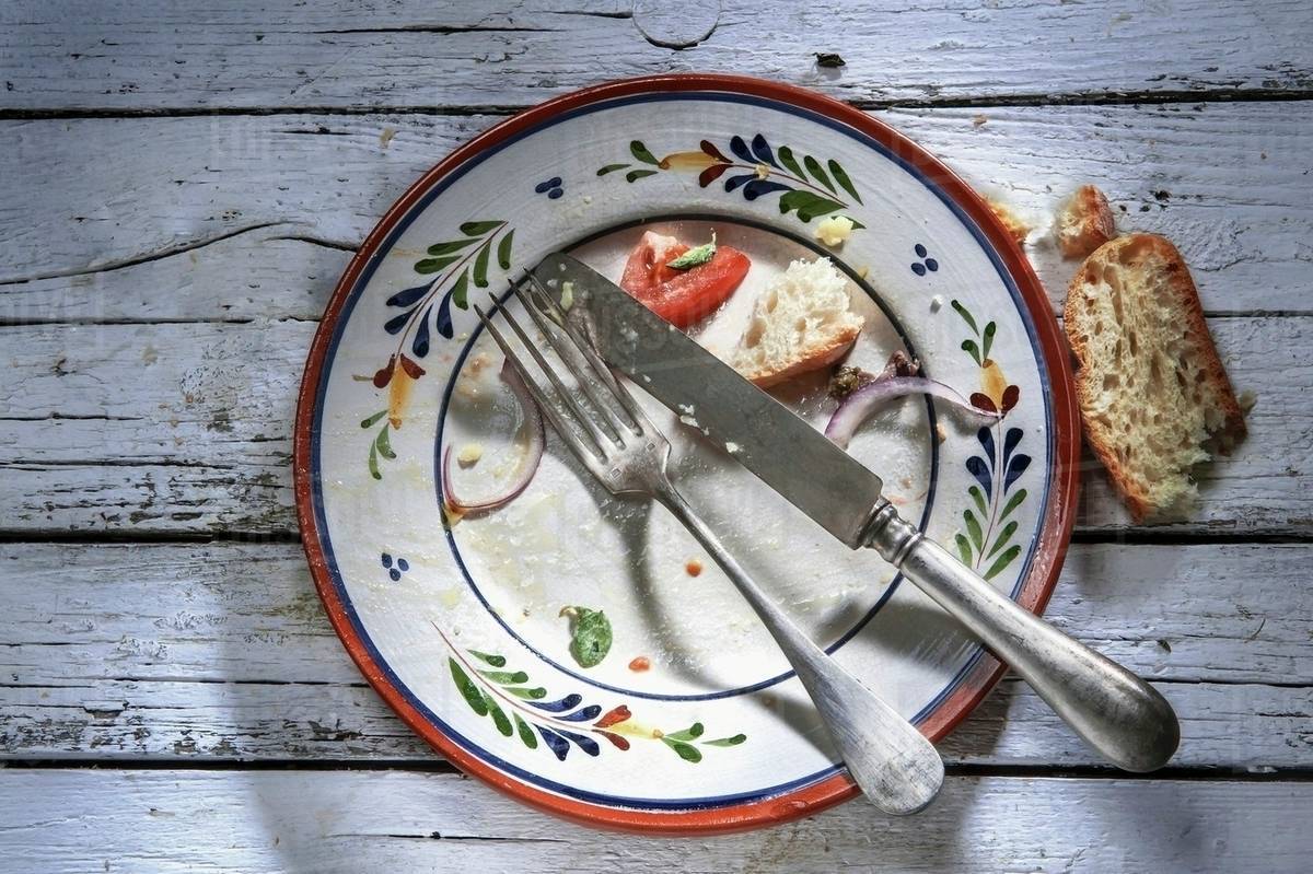 The remains of food and bread on an empty plate - Stock Photo - Dissolve