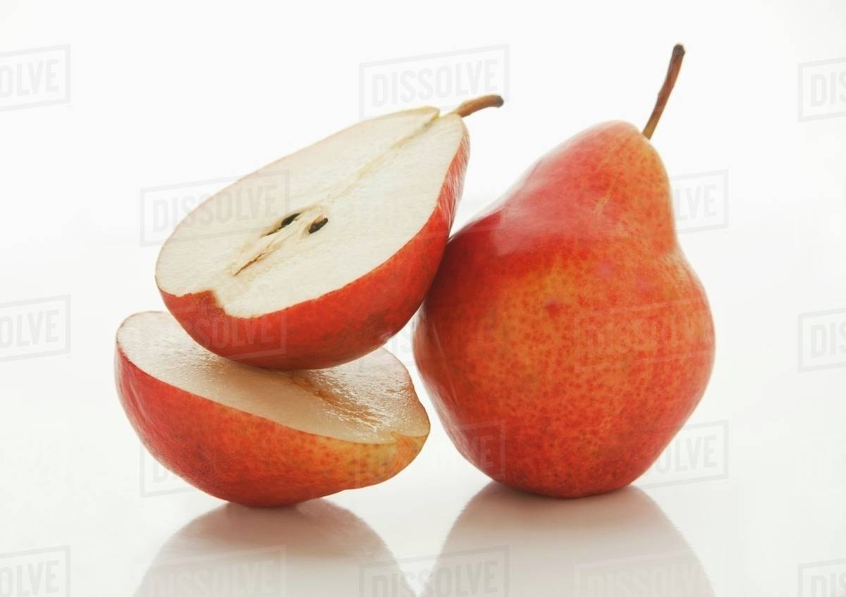 Two red pears, whole and halved, on a white surface - Royalty-free ...