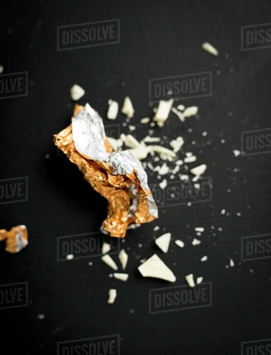 A scrunched-up chocolate wrapper and the remains of chocolate - Stock ...